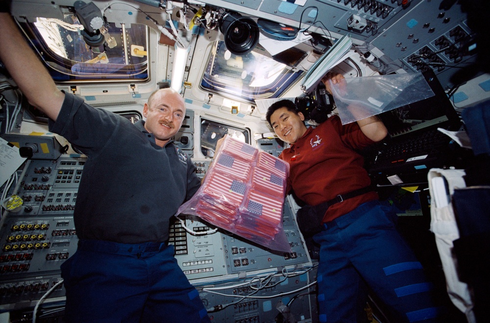 DVIDS - Images - Kelly and Tani pose with 9-11 American flags on the flight deck during STS-108
