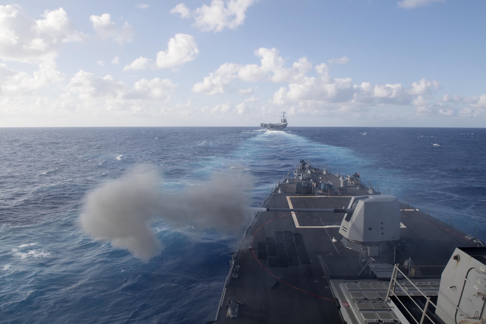 DVIDS - Images - USS Spruance (DDG 111), foreground, fires a MK 45 5-inch gun while sailing in ...